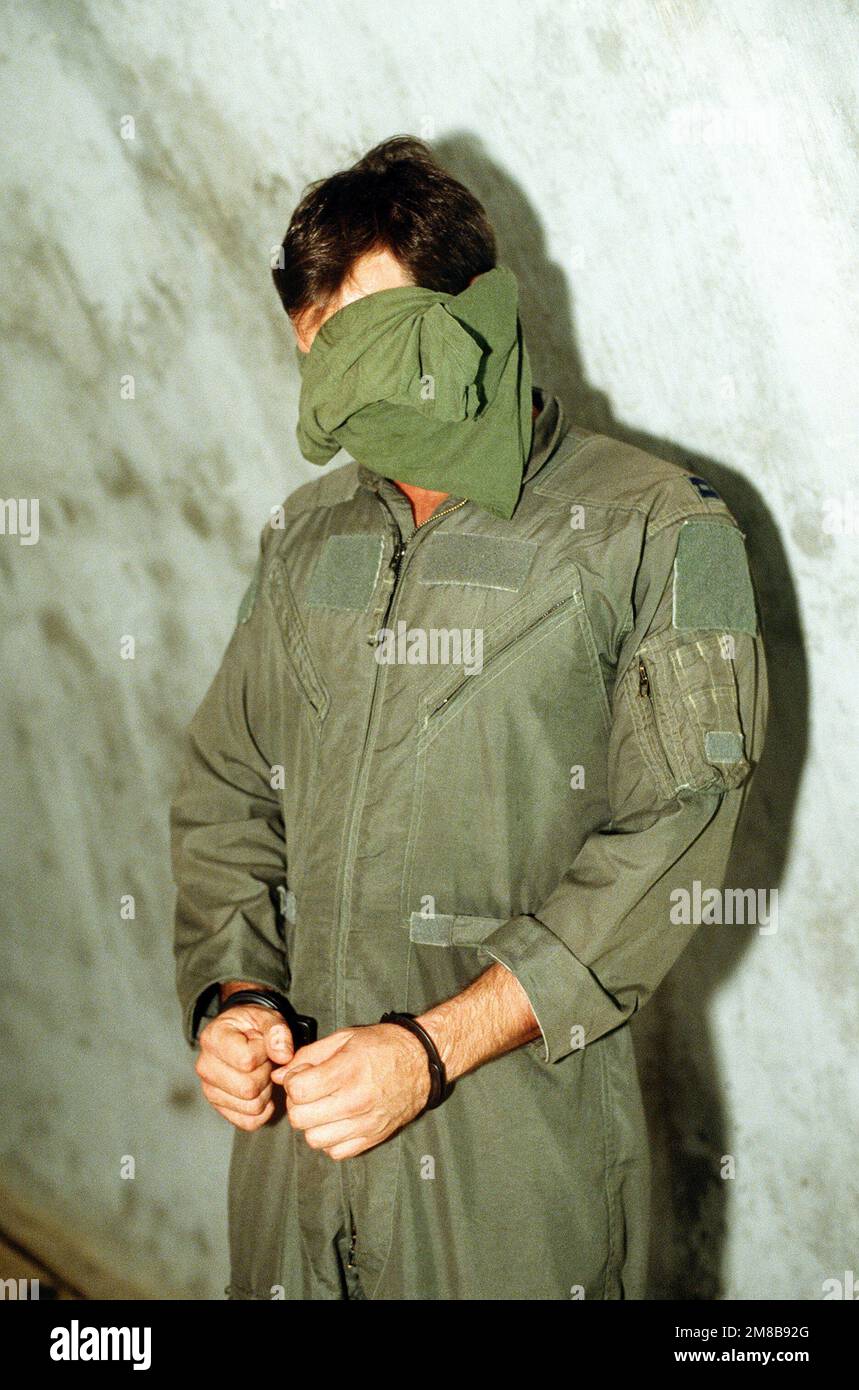 A blindfolded and handcuffed captain stands in an empty munitions ...
