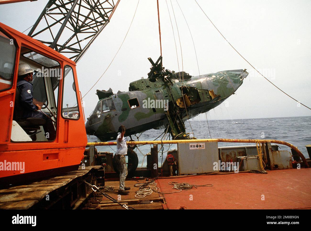 A worker aboard the Japanese salvage ship SHIN TATSU MARU signals to ...