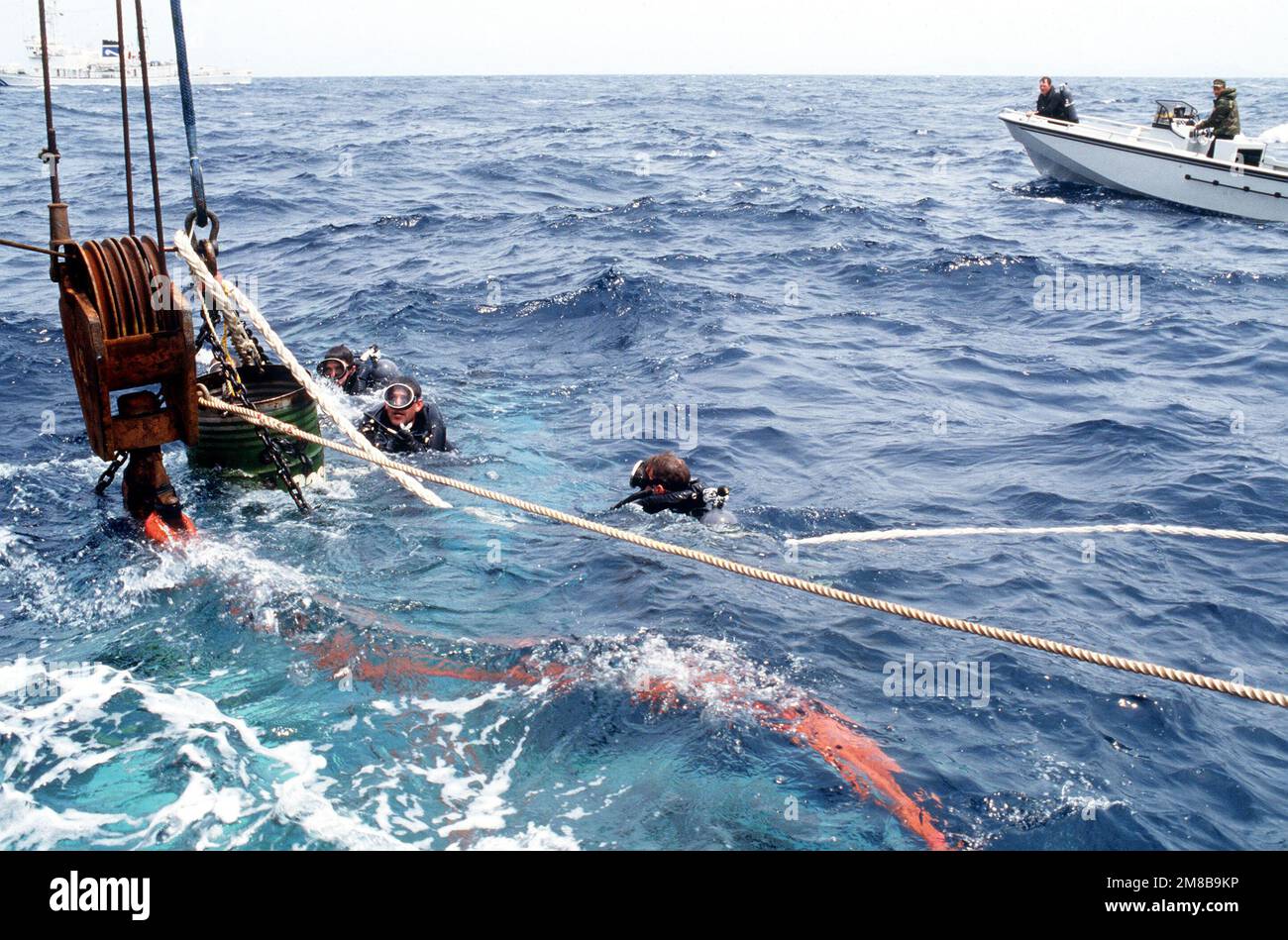 Divers from the 1730th Pararescue Squadron watch as a crane aboard the ...