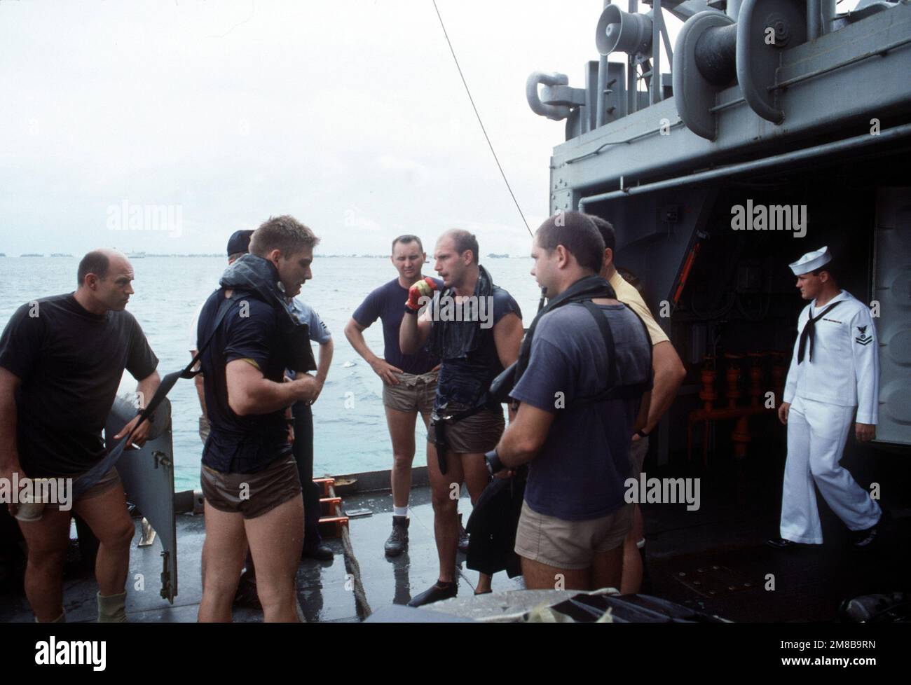 Divers confer aboard the salvage and rescue ship USS BRUNSWICK (ATS-3 ...