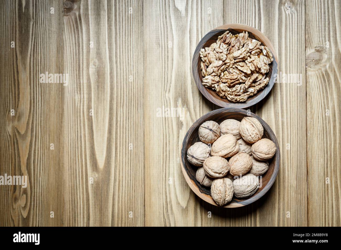 Peeled walnuts and nuts in a shell in walnut wooden bowl on a wooden ...