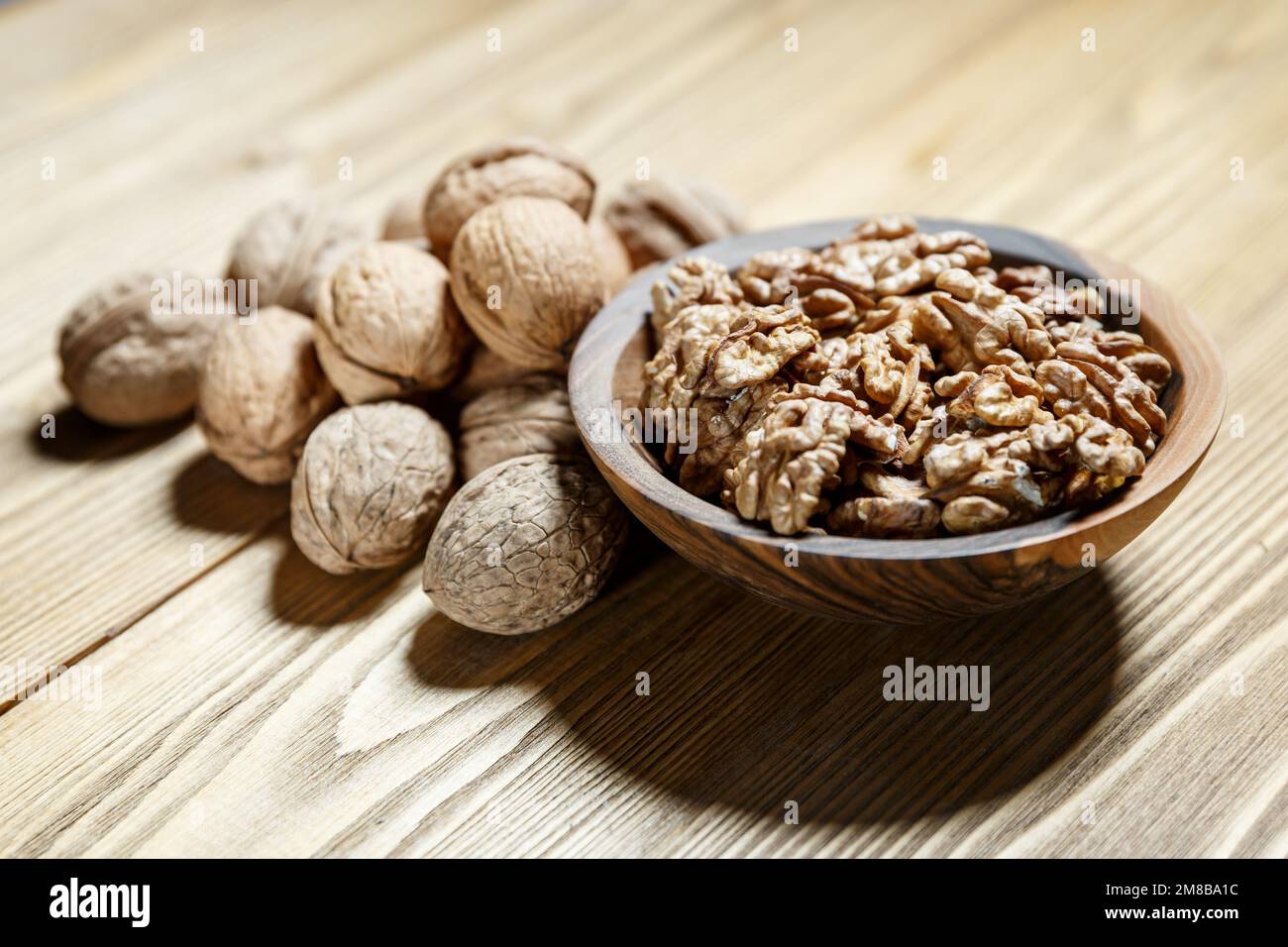 Peeled walnuts and nuts in a shell in walnut wooden bowl on a wooden ...