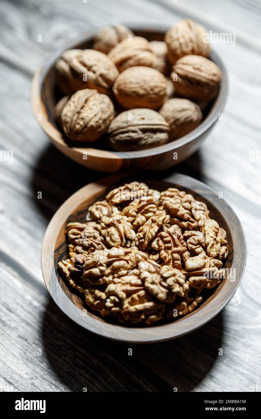 Peeled walnuts and nuts in a shell in walnut wooden bowl on a wooden ...