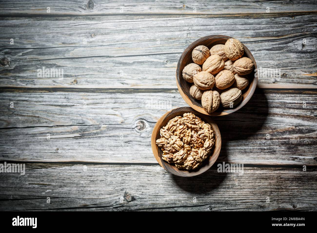 Peeled walnuts and nuts in a shell in walnut wooden bowl on a wooden ...