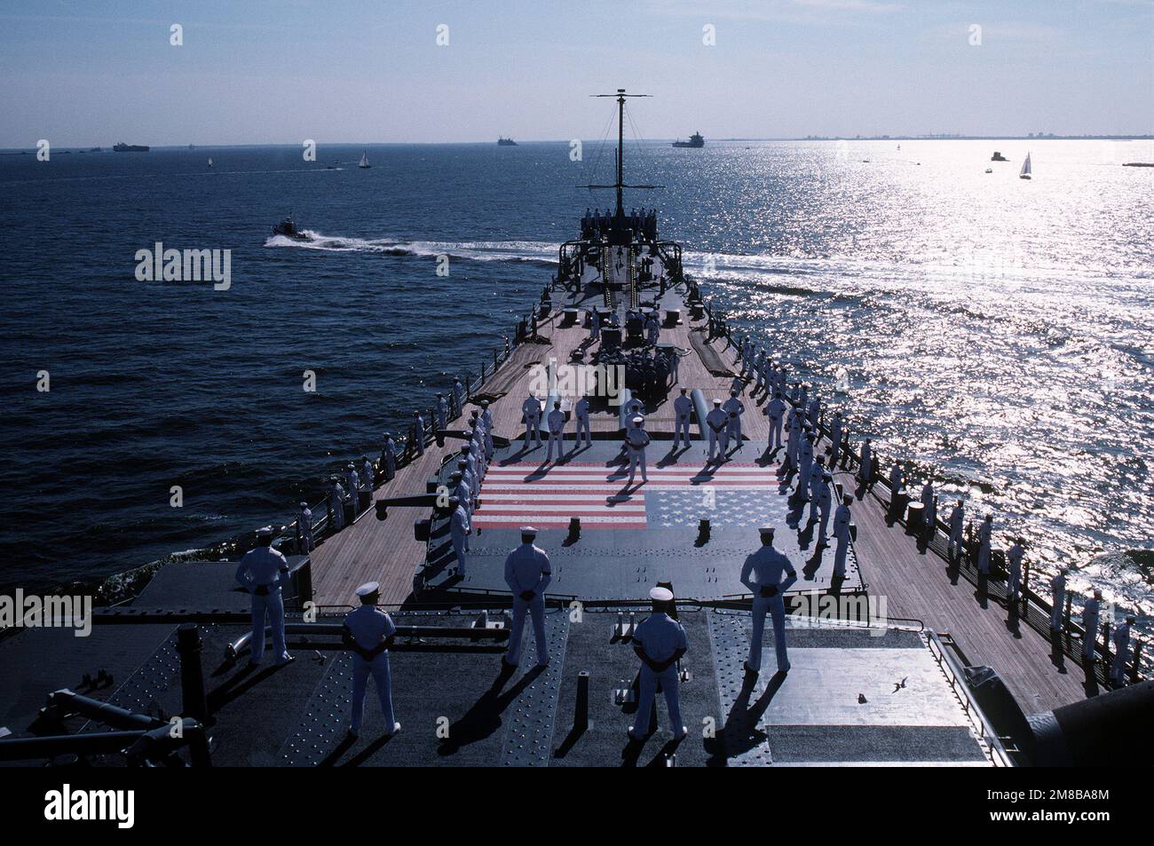 Crew members man the rails and stand atop the 16-inch gun turret aboard ...