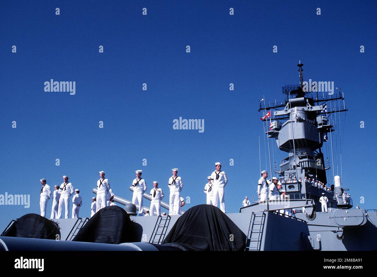 Crew members stand atop the 16-inch gun turret aboard the battleship ...