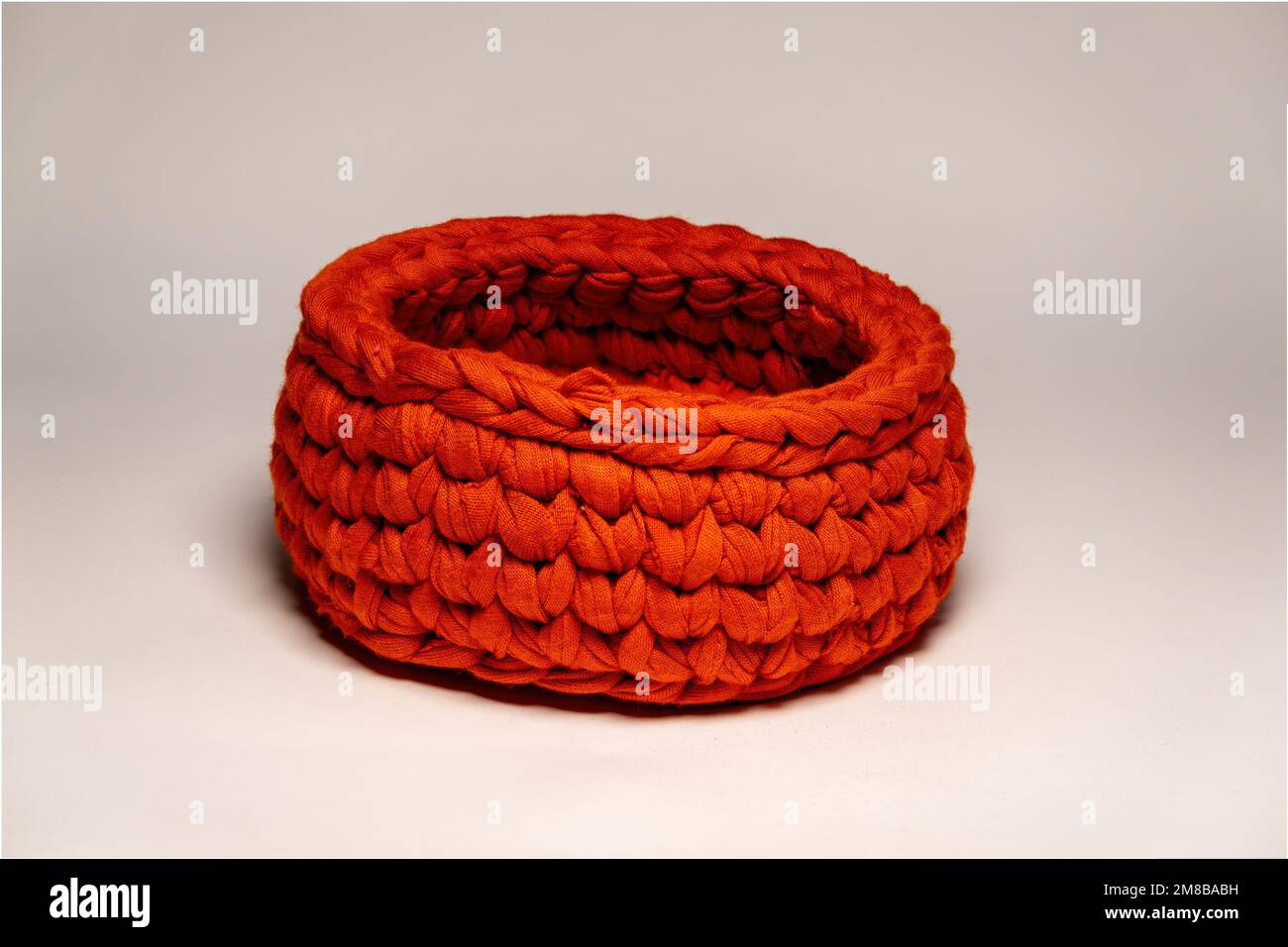 Recycling of materials. A small knitted container in red color is made ...
