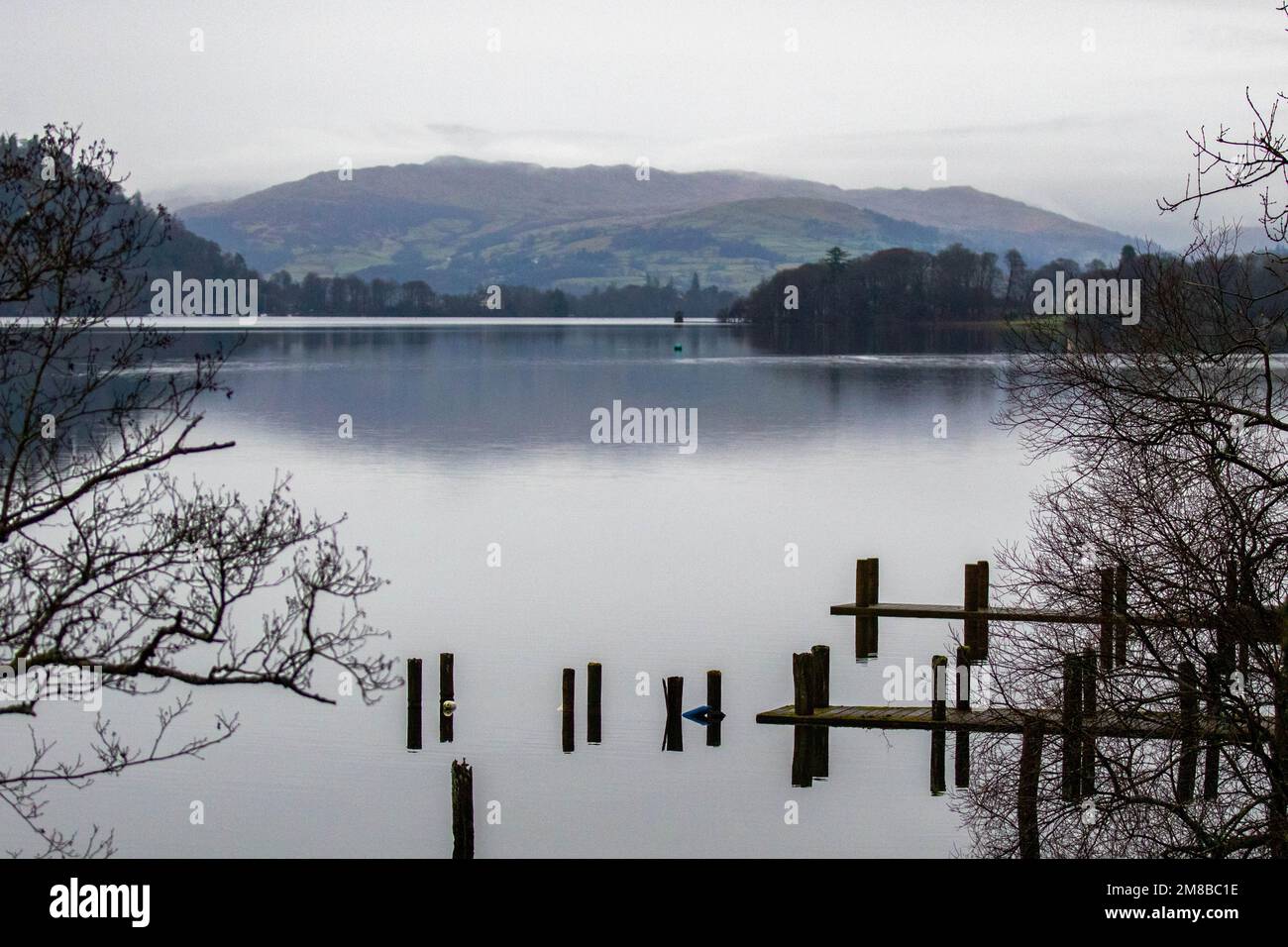 Sunken jetty on lake Windermere surrounded by mountains on a cloudy day ...