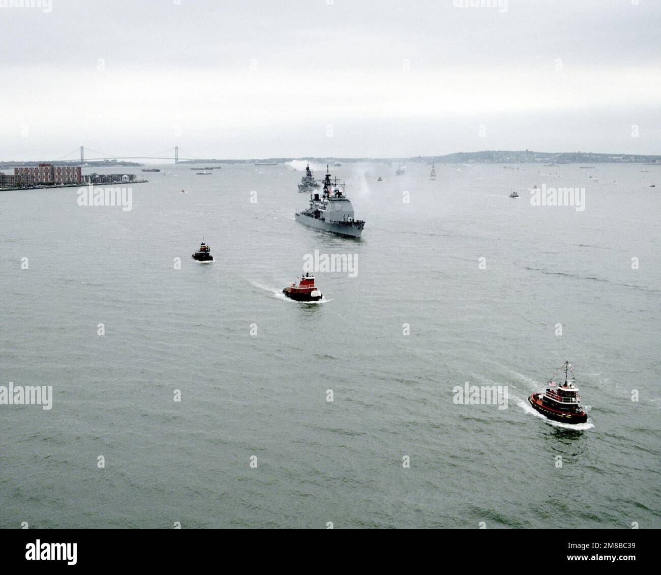 Led by several tug boats, the guided missile cruiser USS TICONDEROGA ...