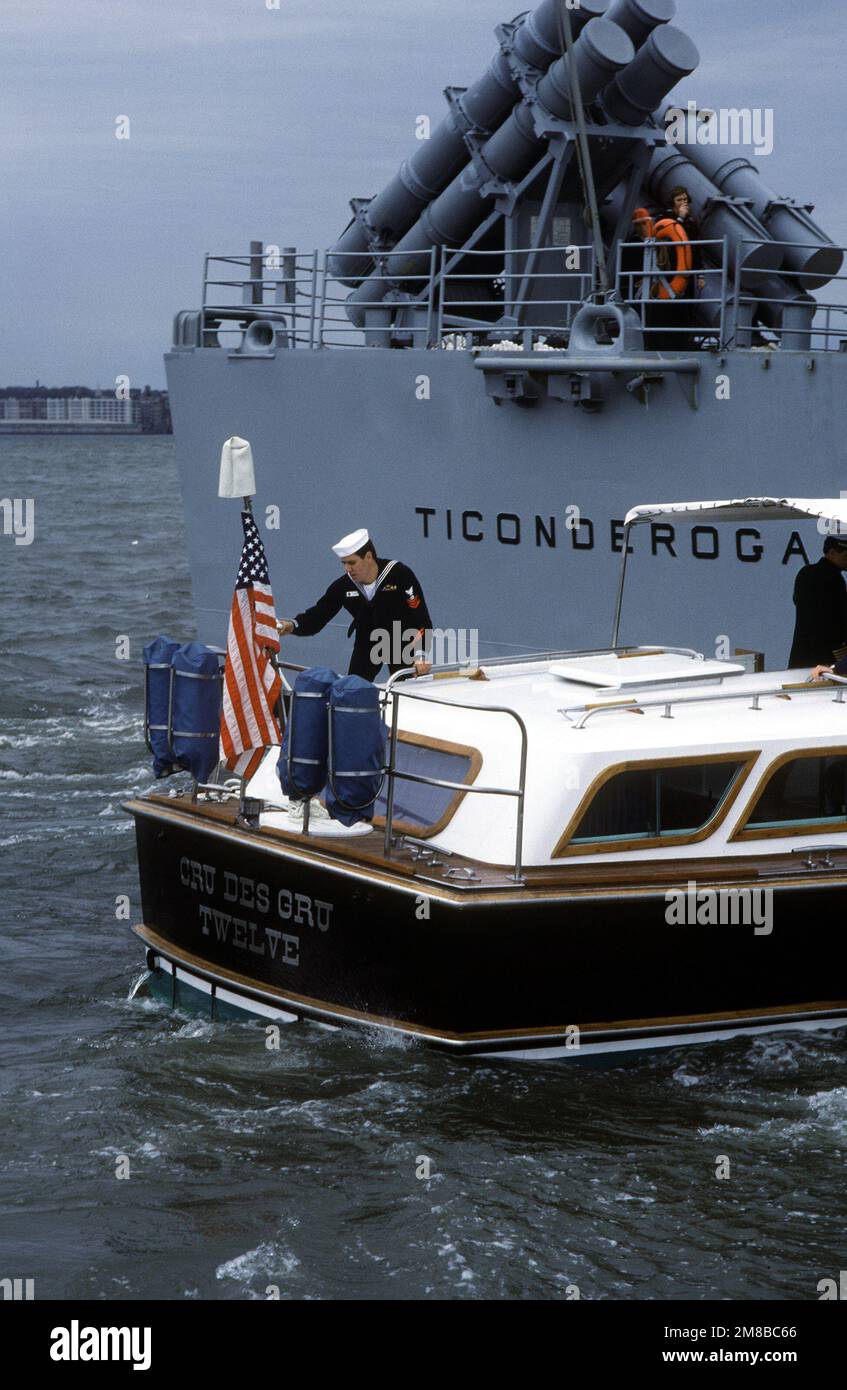 A sailor holds on to the railing on the stern of a Cruiser Destroyer ...