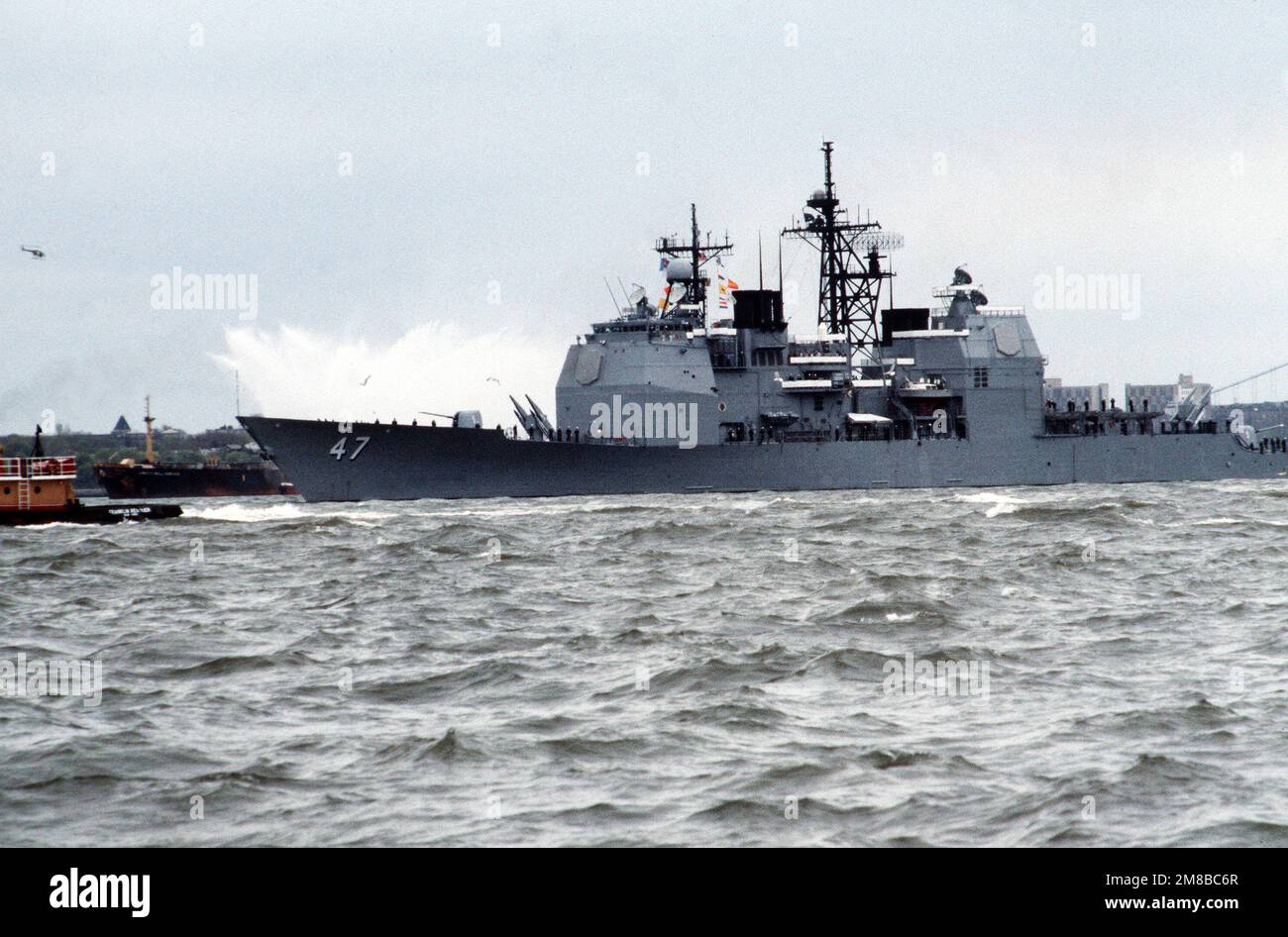 A fire boat hidden from view behind the guided missile cruiser USS ...