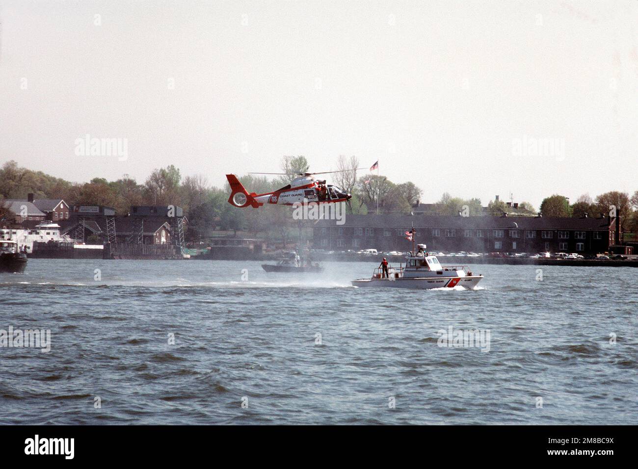 A Coast Guard HH-65A Dolphin helicopter joins a small Coast Guard craft ...