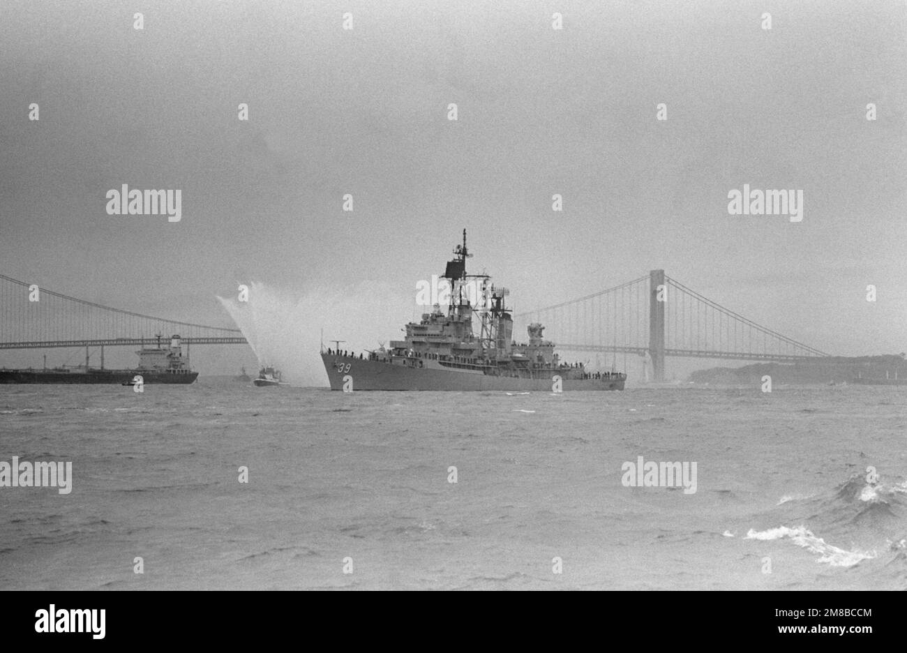A fire boat sprays streams of water as the guided missile destroyer USS ...