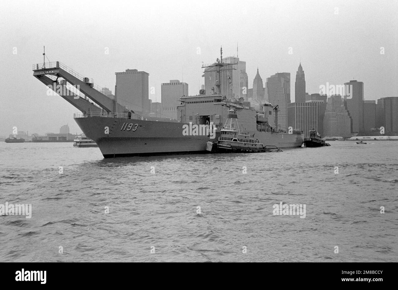 Tug boats guide the tank landing ship USS FAIRFAX COUNTY (LST 1193 ...