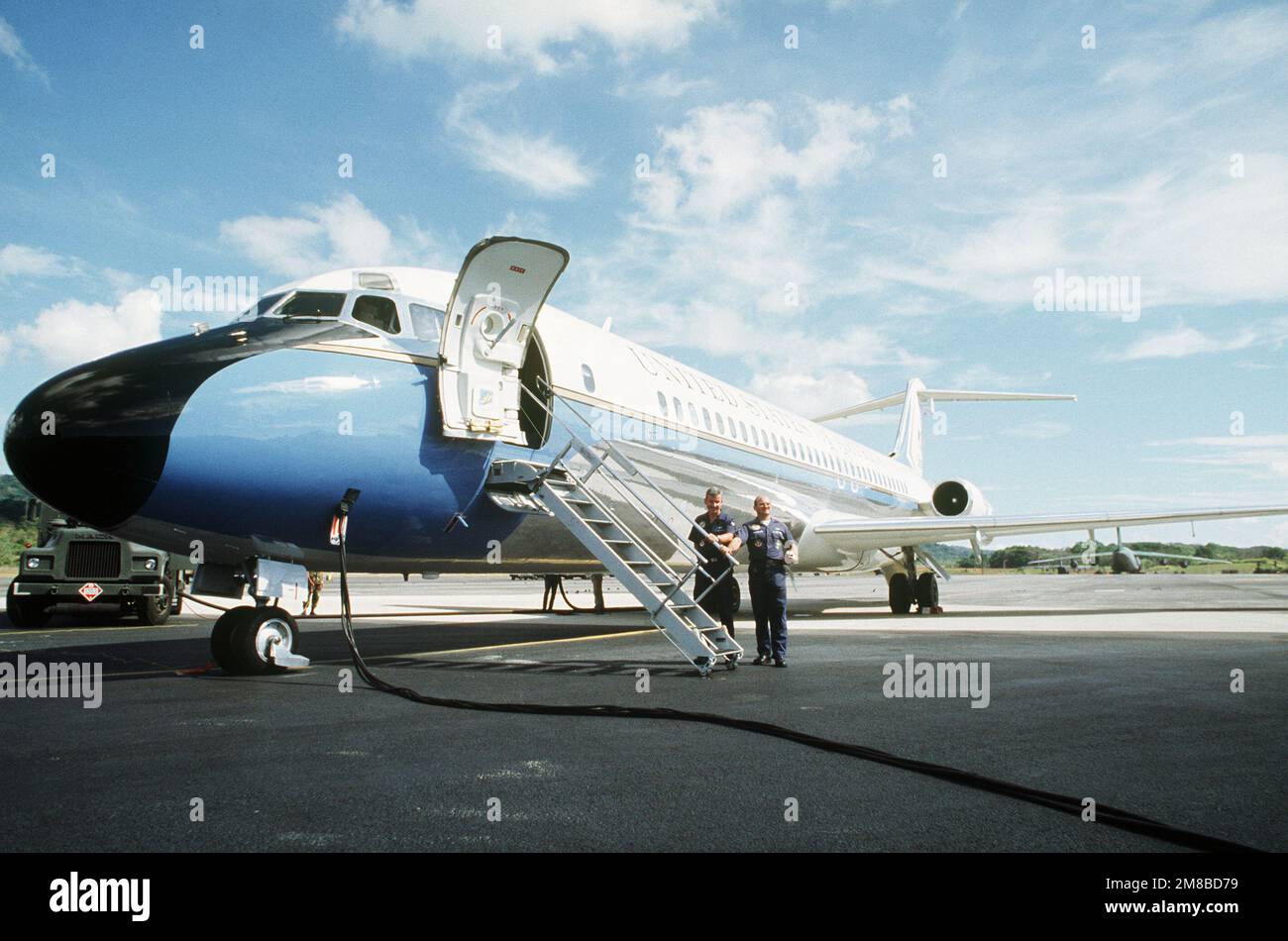 Crew members wait on the runway at the door of a C-9C Nightingale ...