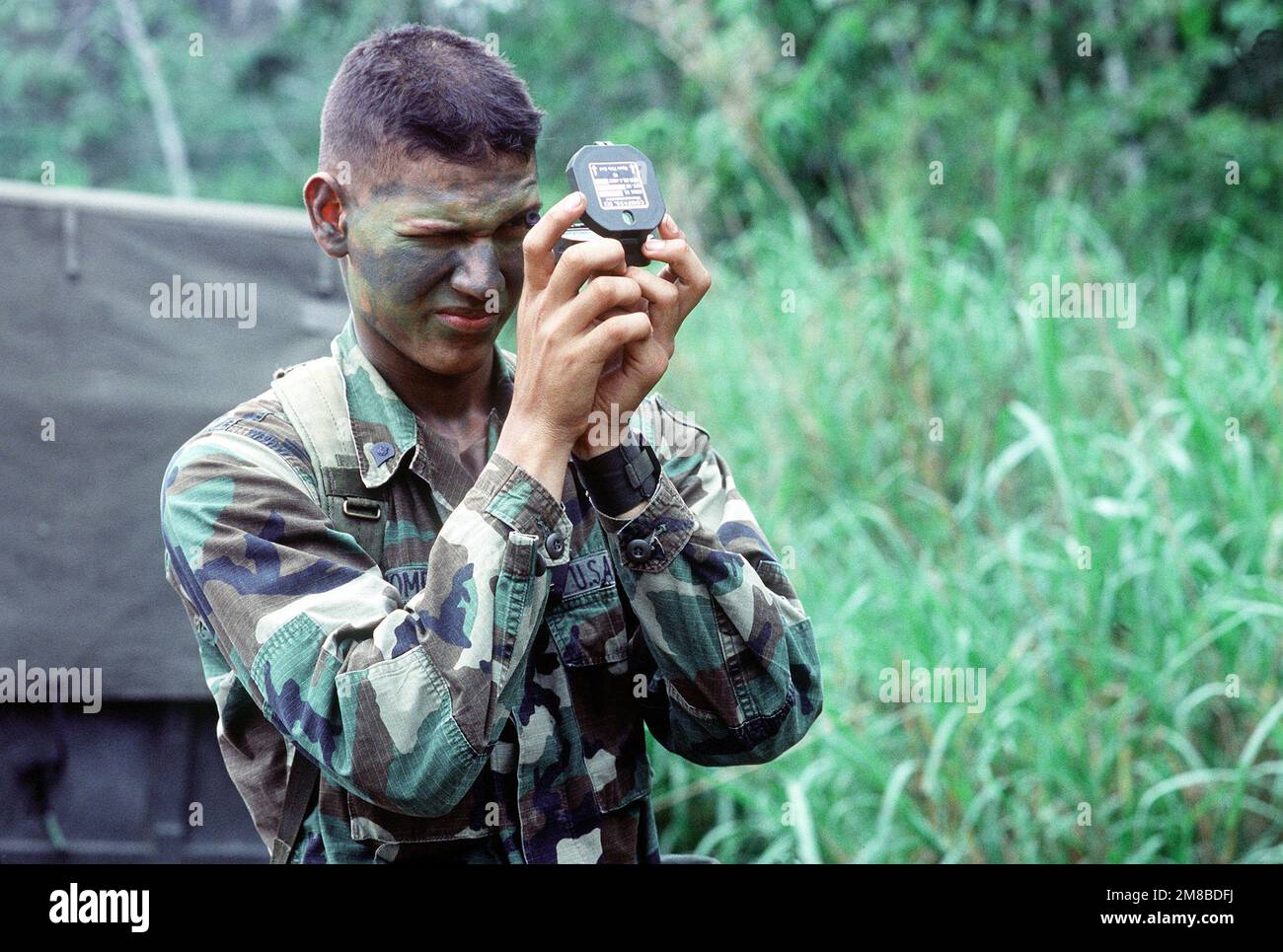 A soldier on a jungle operations training exercise takes a reading with ...