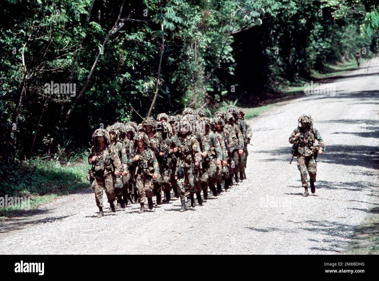 A unit marches down a road during jungle training. Base: Fort Sherman ...