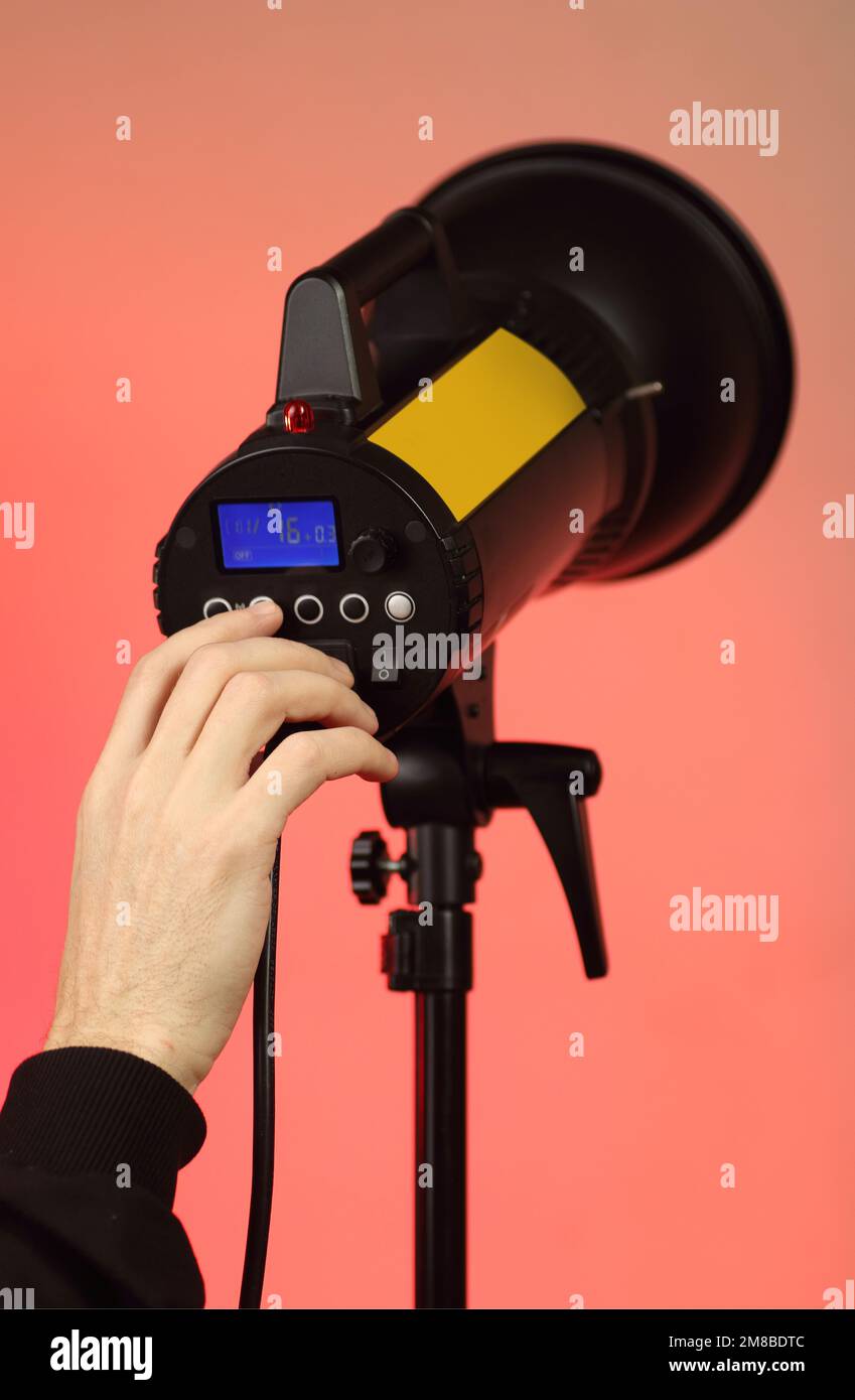 setting a studio flash on the back panel by a person on a pink ...