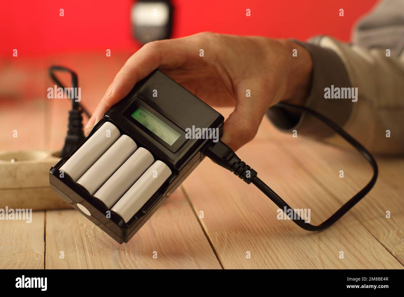 charger with batteries in a person's hand on a colored background Stock ...