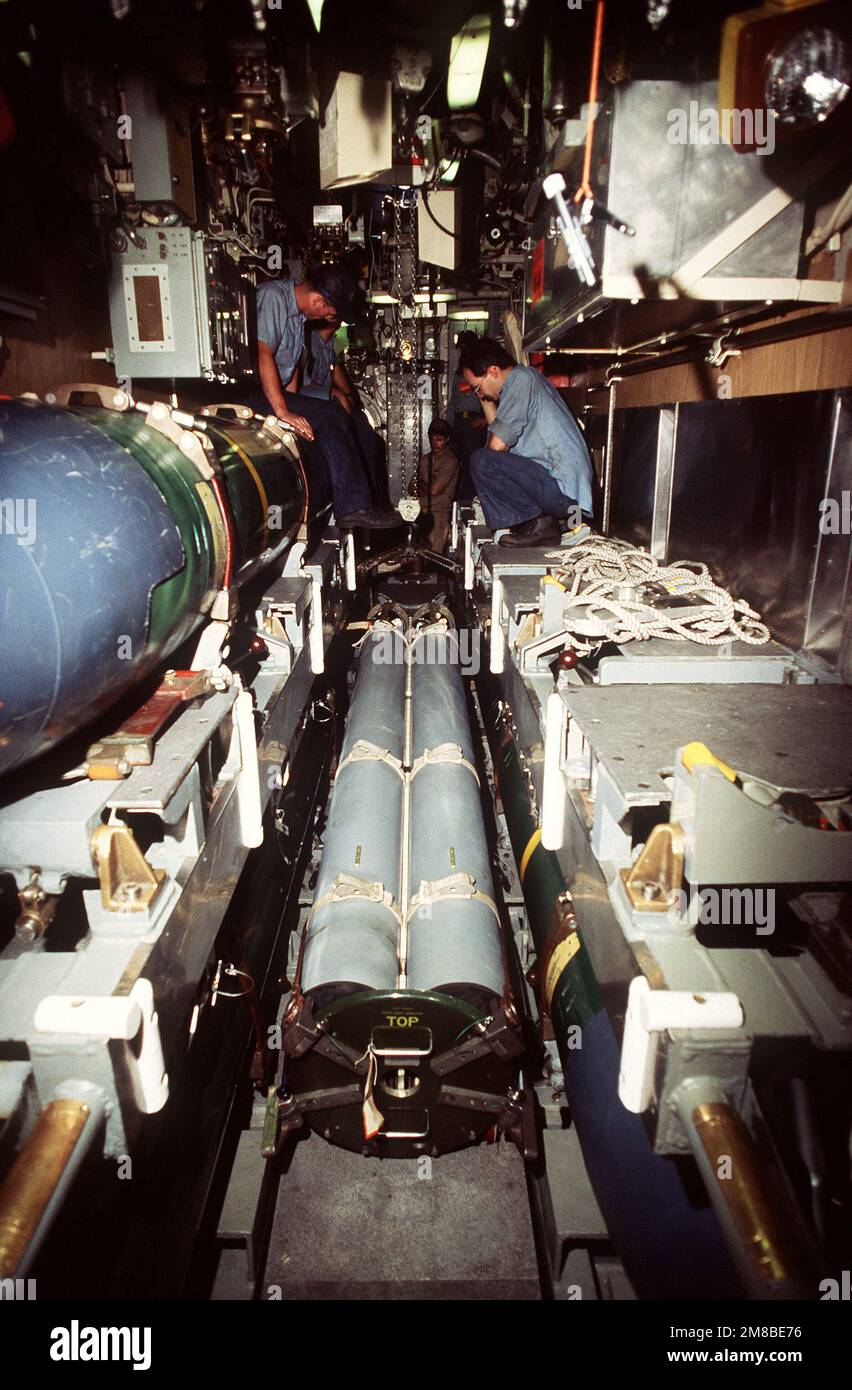 Crewmen keep clear of the deck as a pair of torpedoes is brought into a ...