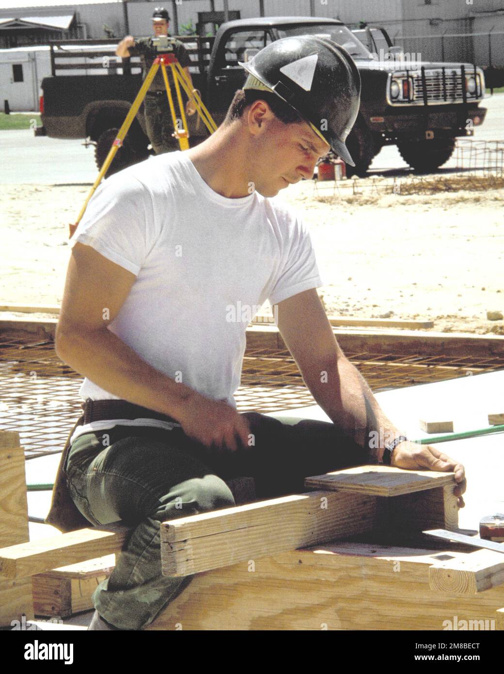 A Seabee hammers together a crossbeam for a new building. Base: Naval ...