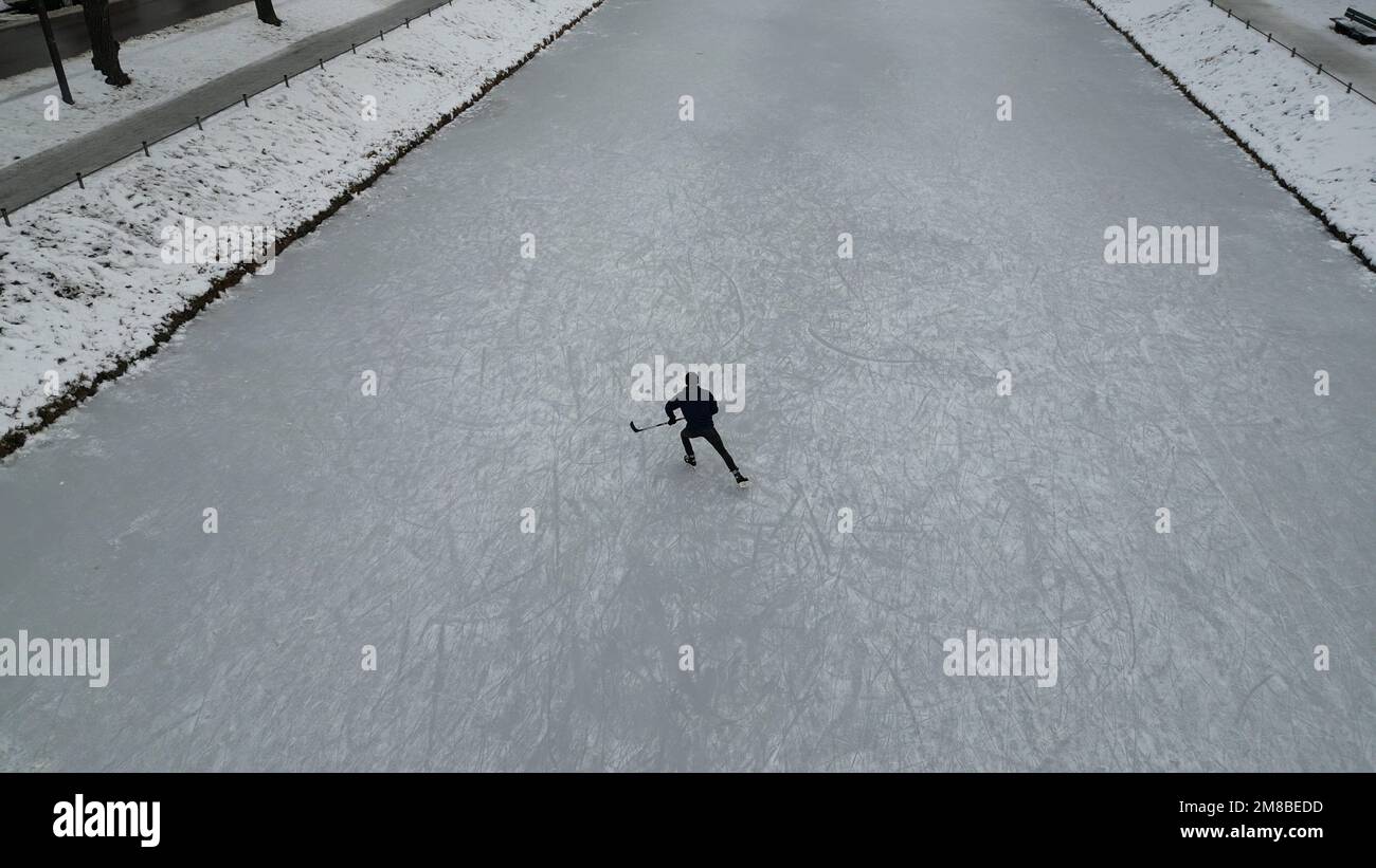 A male in a black outfit holding a hockey stick and skating on an ice ...