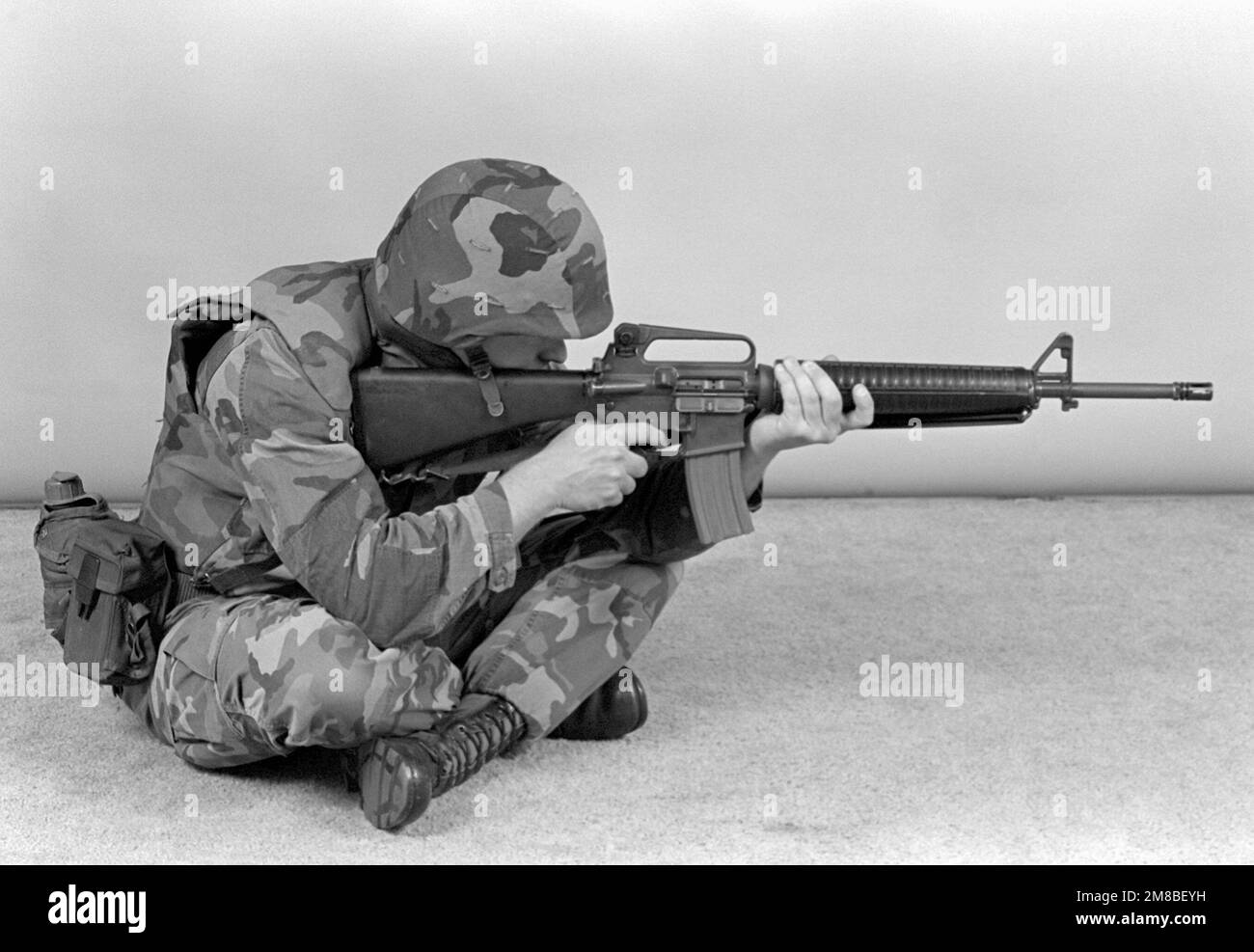 A Marine demonstrates a sitting firing position with an M-16A2 5.56mm ...