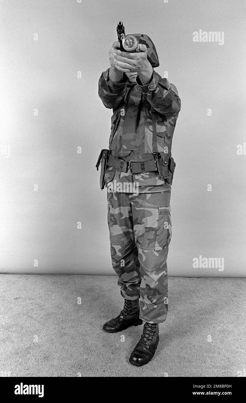 A Marine demonstrates a standing firing position with an M-9 9mm pistol ...