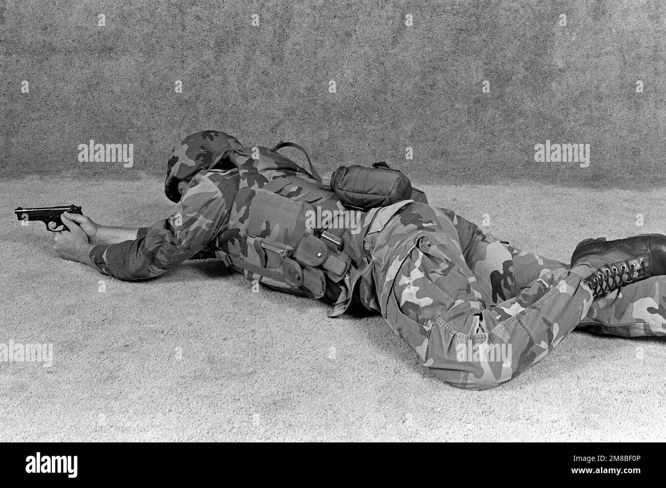 A Marine demonstrates a prone firing position with an M-9 9mm pistol ...