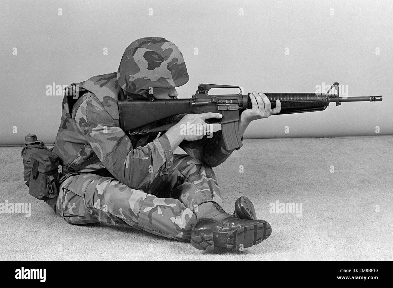A Marine demonstrates a sitting firing position with an M-16A2 5.56mm ...