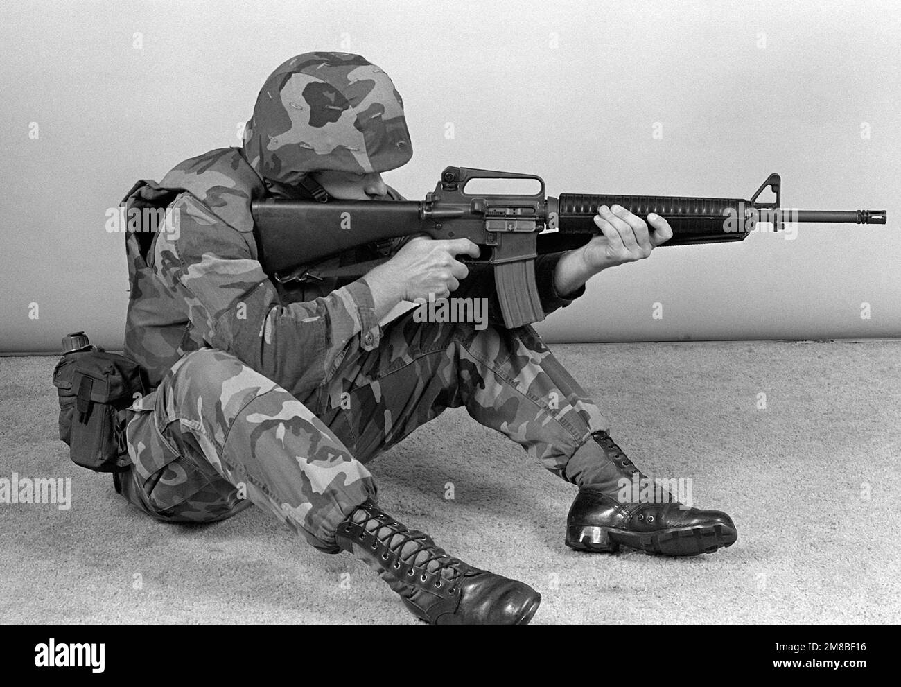 A Marine demonstrates a sitting firing position with an M-16A2 5.56mm ...