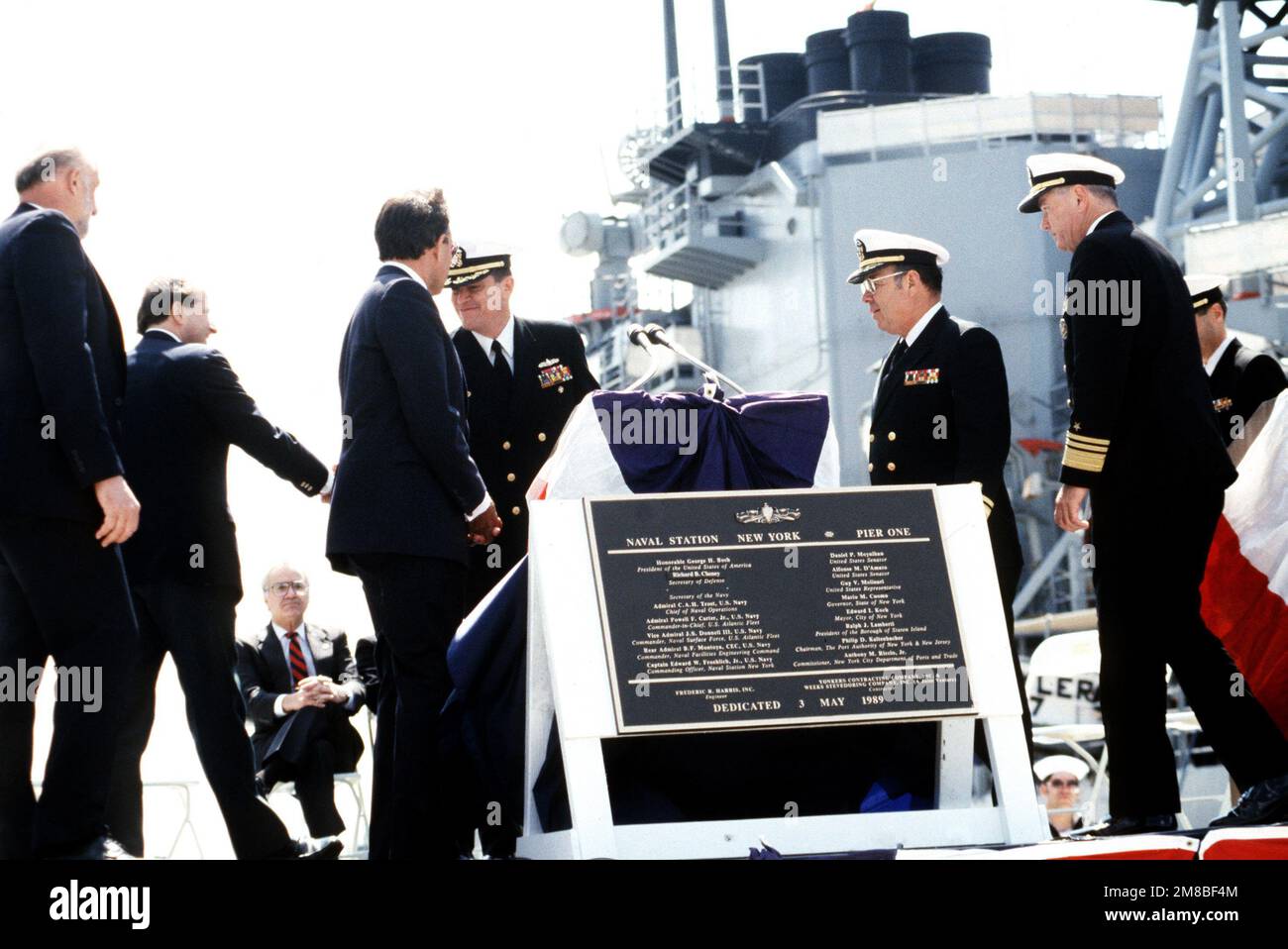 Civilian dignitaries and senior Navy officers congratulate one another ...