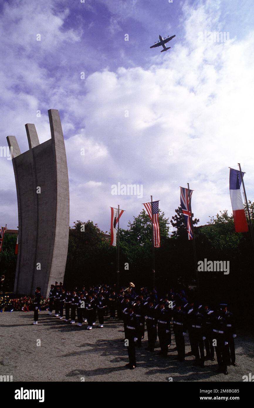 An honor guard and military band salute as a C-130 Hercules aircraft of ...