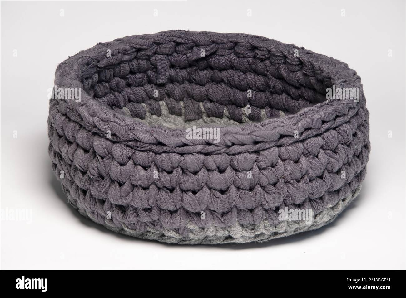 Recycling of materials. A small knitted container in gray color is made ...