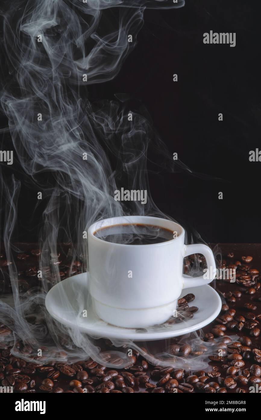 A vertical shot of a cup of hot coffee surrounded by coffee beans ...