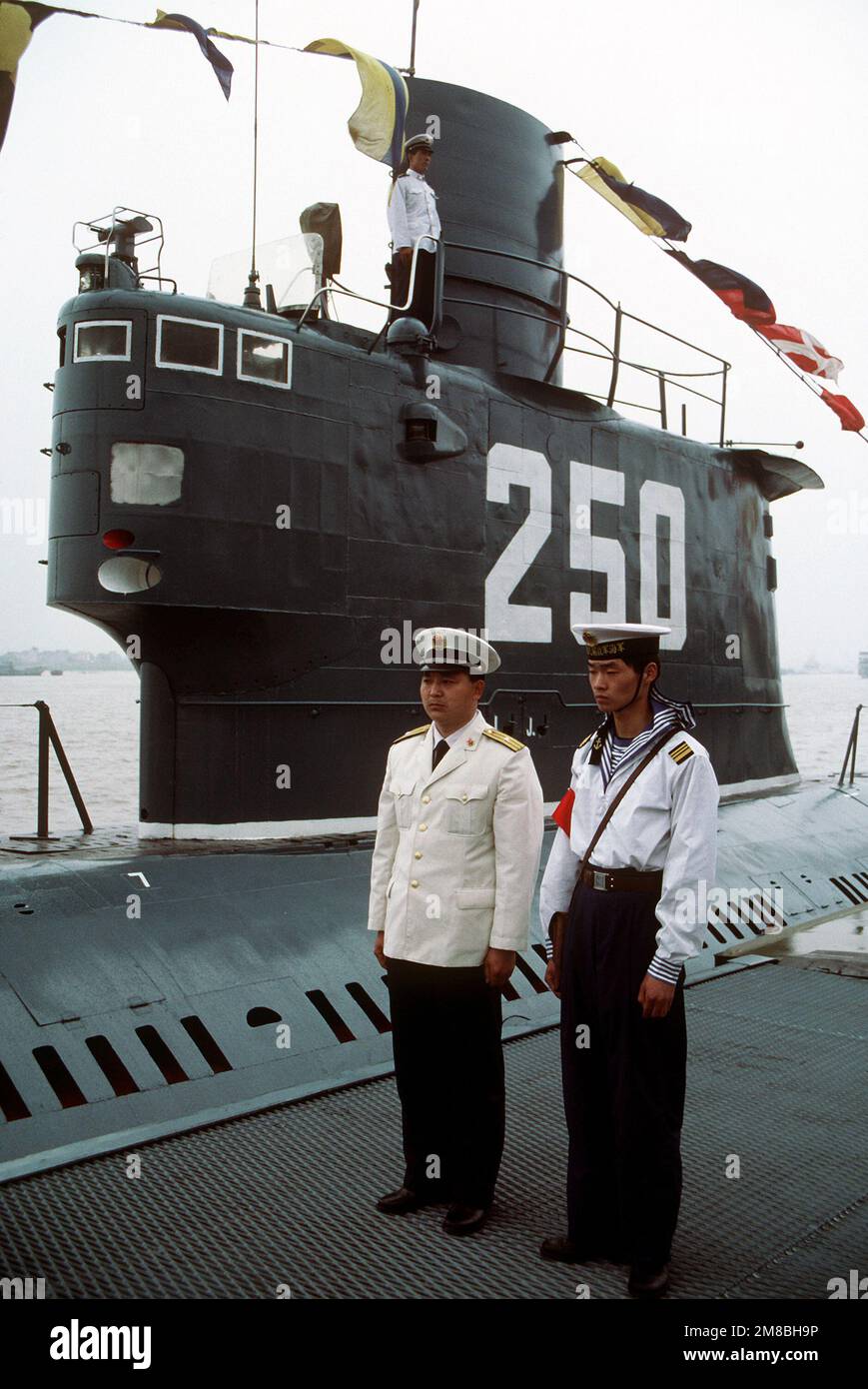 An officer and sailor stand on the pier beside a Chinese navy Romeo ...