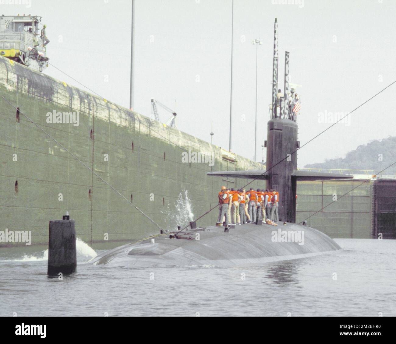 Officers and crew stand on the deck and sail of the nuclear powered attack submarine USS ...