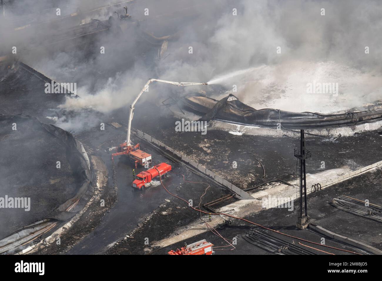 An aerial shot of firefighters putting out a fire in fuel tanks at the ...