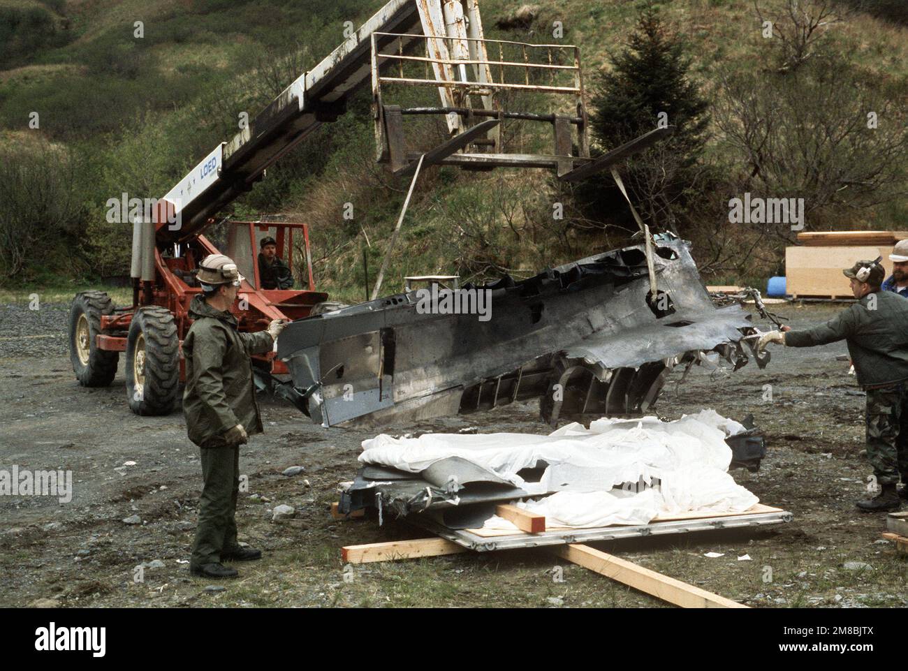A rough terrain forklift is used to stack aircraft wreckage onto a ...