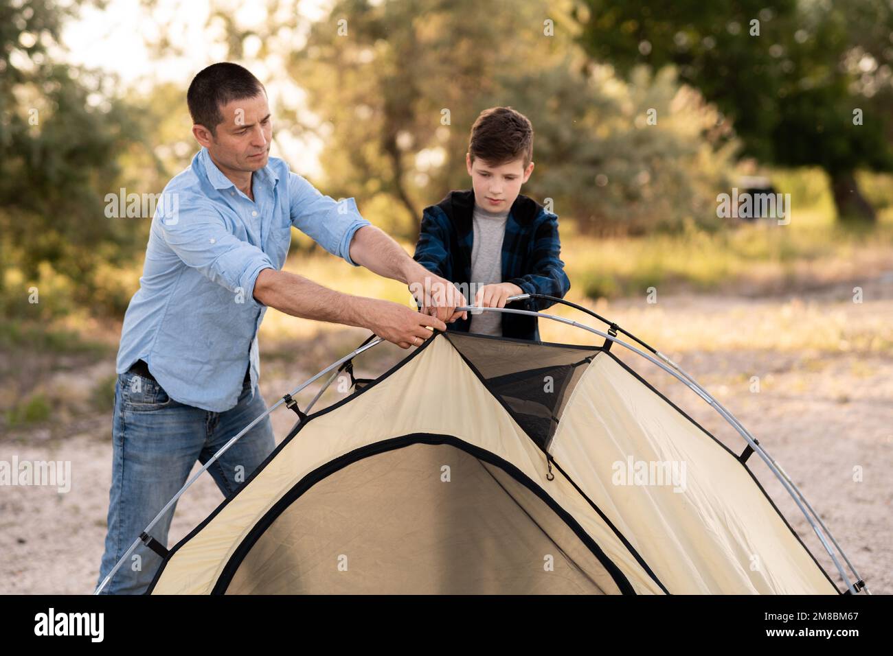 Father learn his son set up camping tent on summer forest glade ...