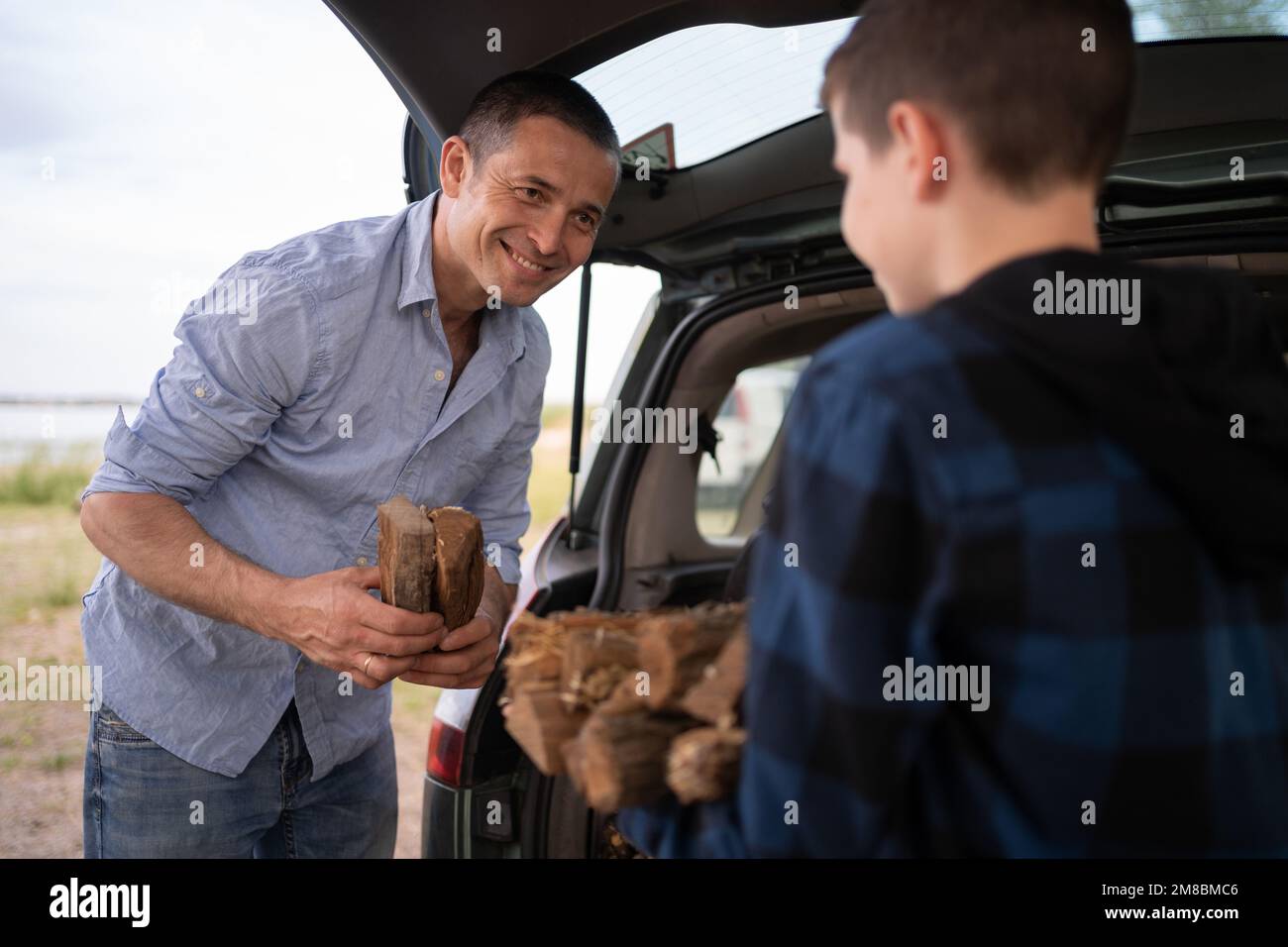 Father's day in nature. Son and father getting firewood from the car ...