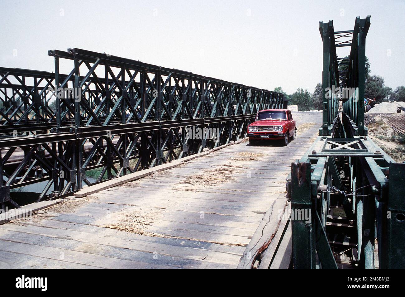 An automobile crosses a Bailey Bridge in use on the road between ...