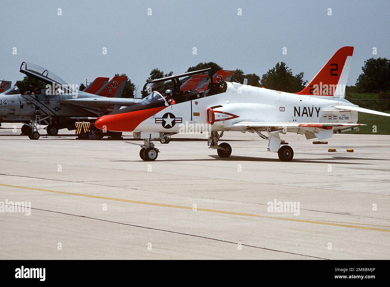A test pilot taxis a T-45A Goshawk aircraft past a row of F-14A Tomcat ...