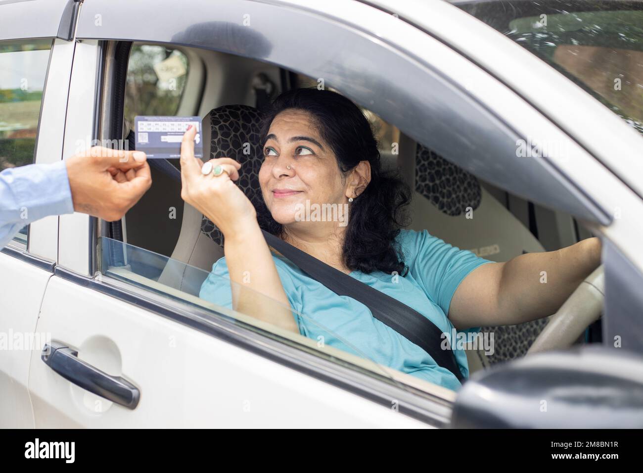 Happy indian mature woman sitting in car wearing seat belt give credit ...