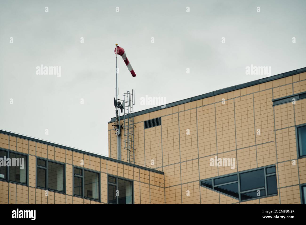 A wind indicator on the top of the building under a cloudy sky Stock ...
