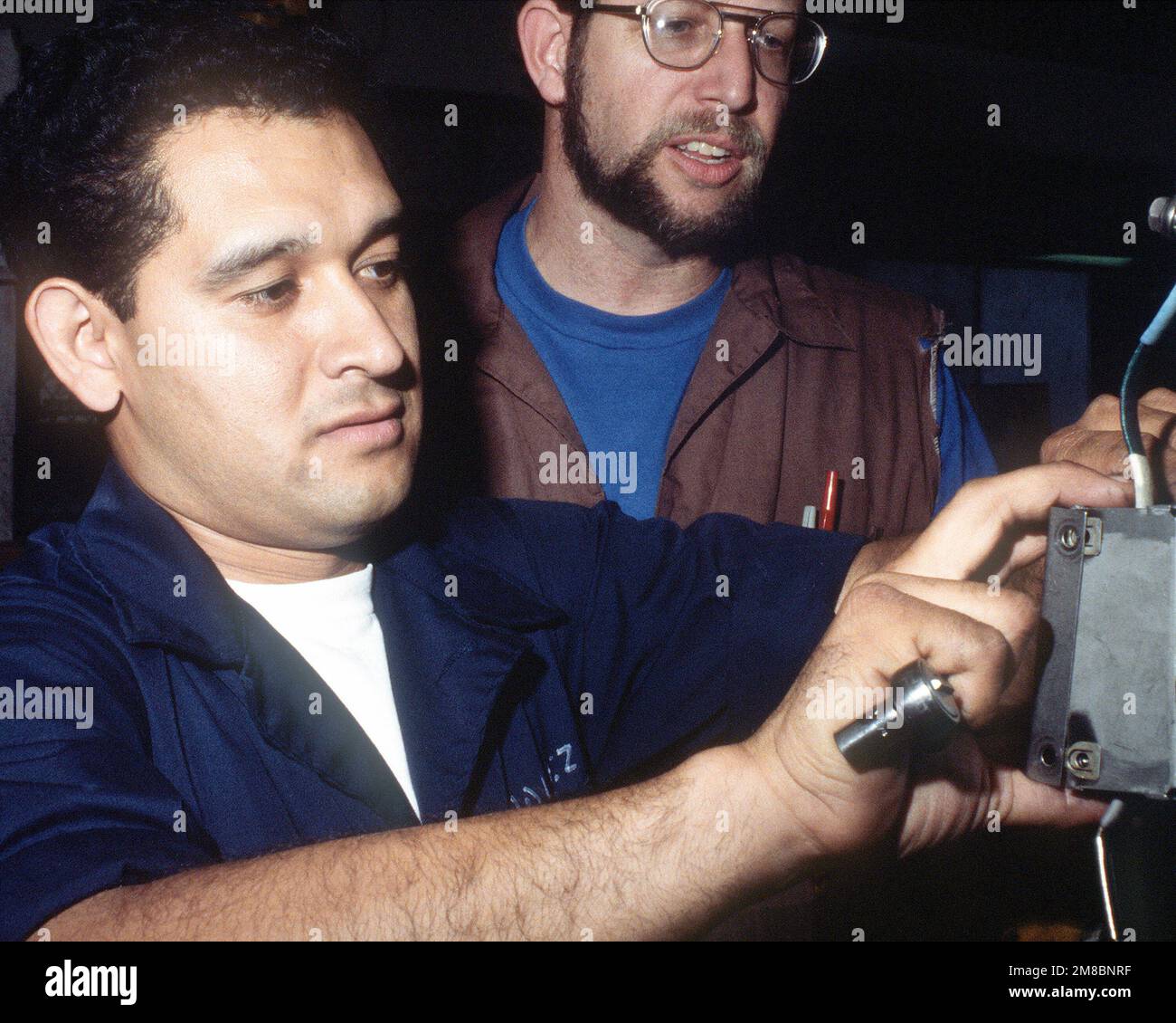 An aviation machinist's mate 2nd class and a civilian work together ...