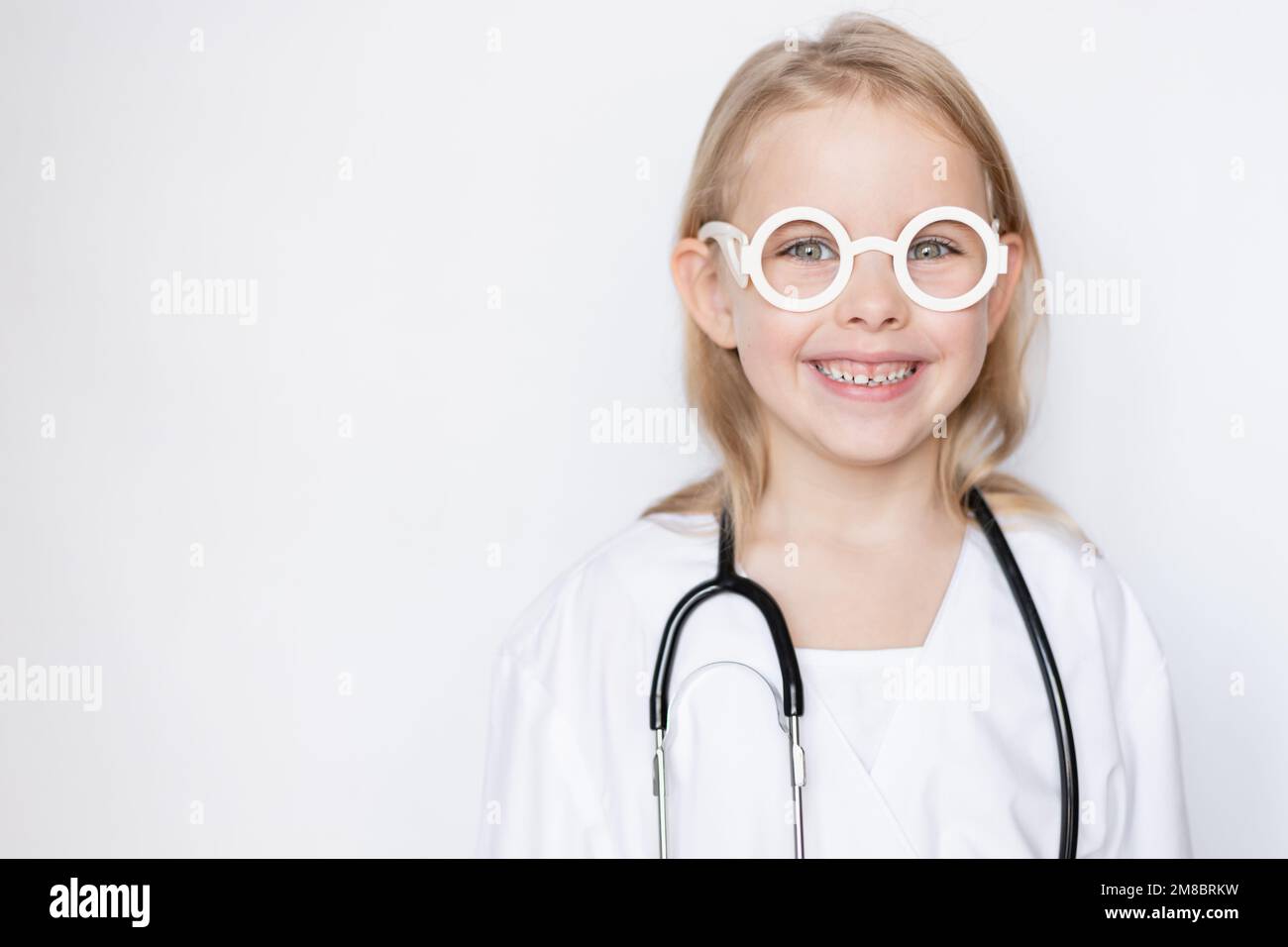 Close-up portrait of cute little girl dressed up in doctor attire with ...