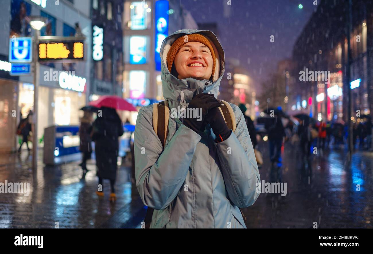 snowfall woman in a blue jacket and yellow hat christmas outside, city ...