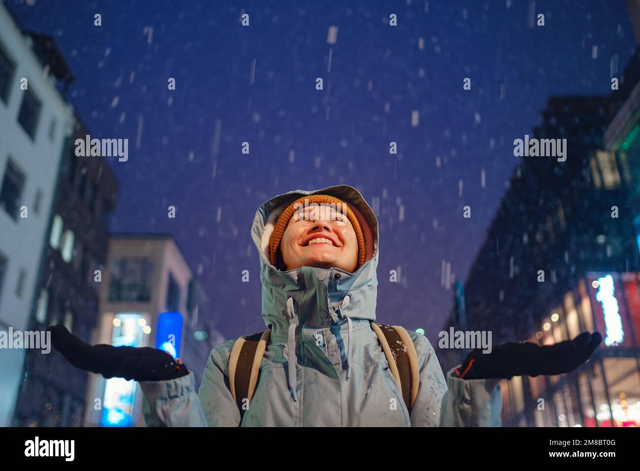 snowfall woman in a blue jacket and yellow hat christmas outside, city ...