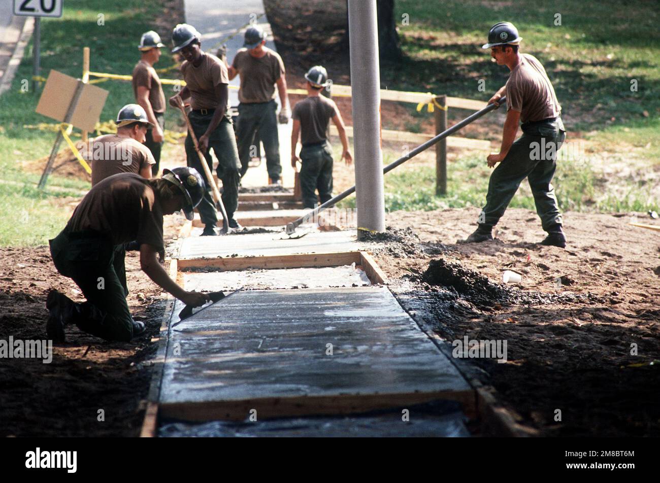 Seabees of Construction Battalion Unit 402 (CBU 402) use a steel trowel ...